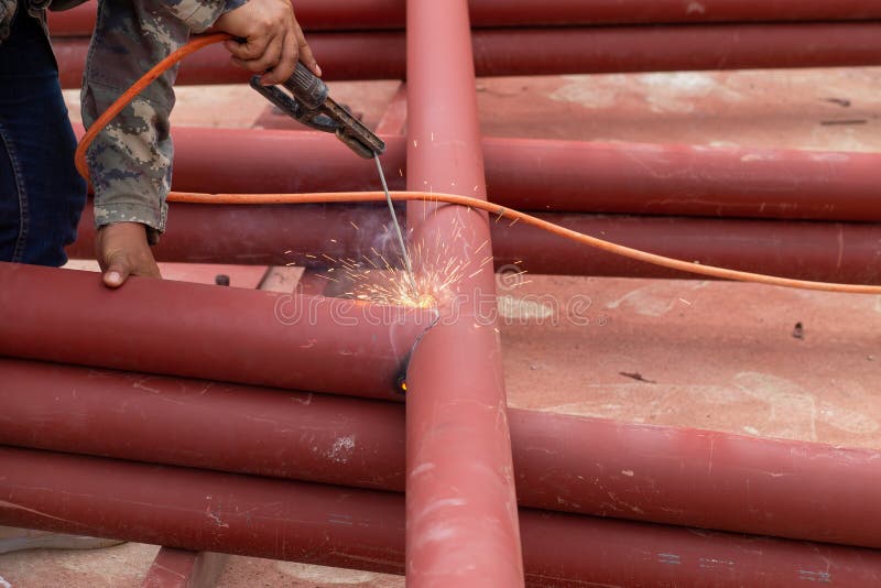 A Large Red Iron Pole Being Welded by a Welder on the Construction Site ...