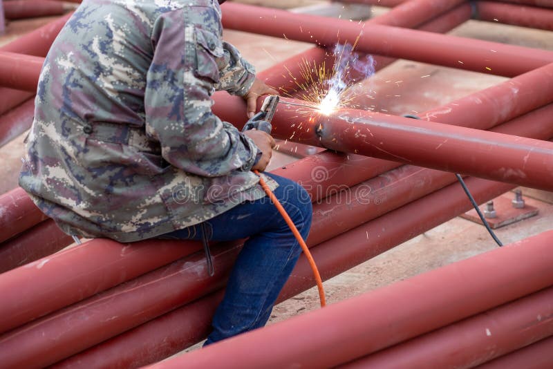A Large Red Iron Pole Being Welded by a Welder on the Construction Site ...
