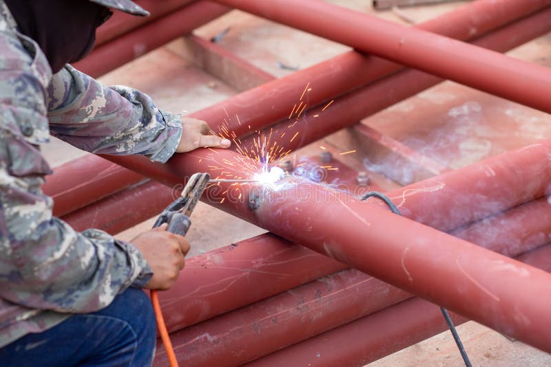 A Large Red Iron Pole Being Welded by a Welder on the Construction Site ...