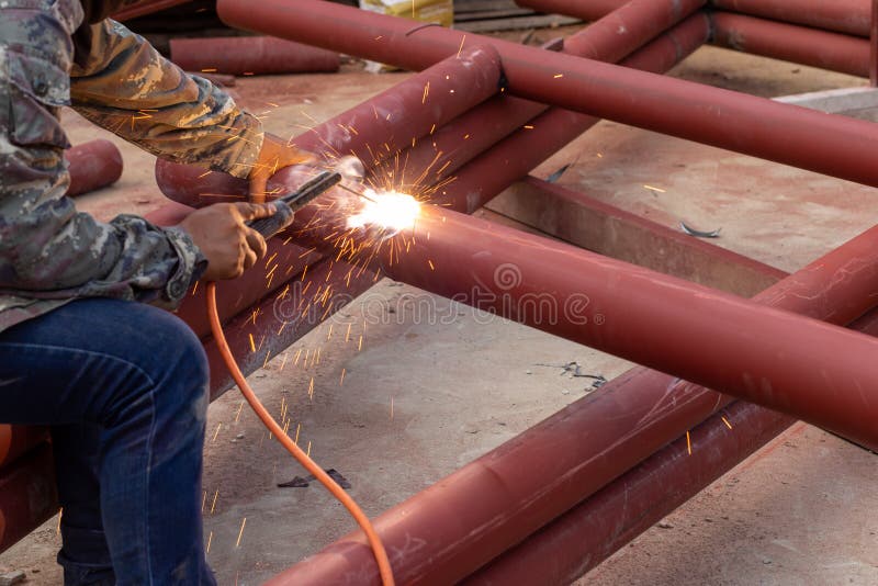 A Large Red Iron Pole Being Welded by a Welder on the Construction Site ...