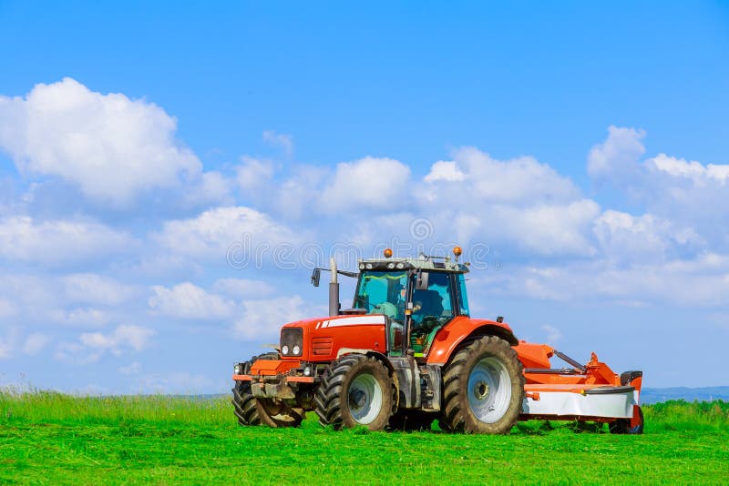 Large Red Tractor with a Mower Mows the Grass on a Field on a Sunny Day ...