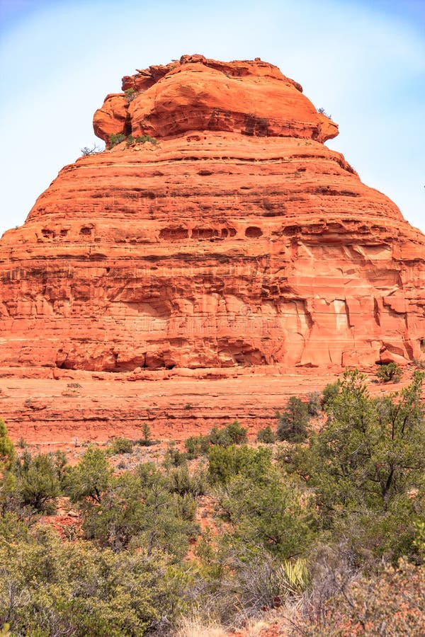 A Large Rock Formation with a Green Bush in Front of it Stock Photo ...