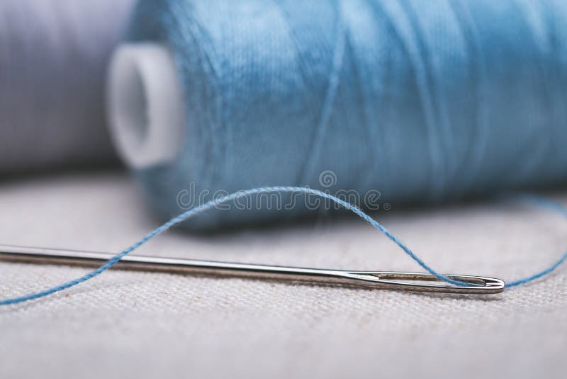 On Blue Surface There are Blue Threads on Reel, Sewing Needle with ...