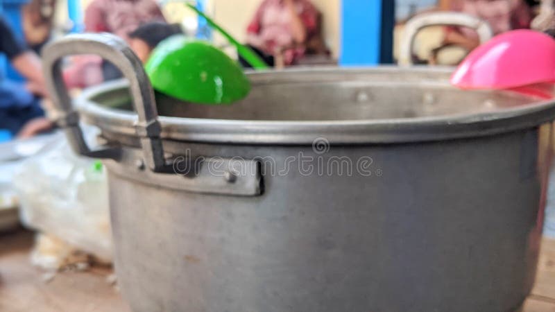 A Large, Silver Pot Filled with a Liquid. Two Dippers, One Green and ...