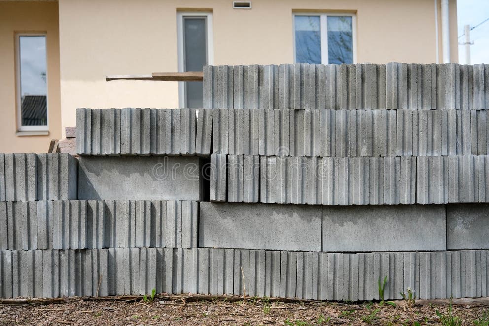 A Large Stack of Gray Concrete Blocks is Piled Up in Front of a ...