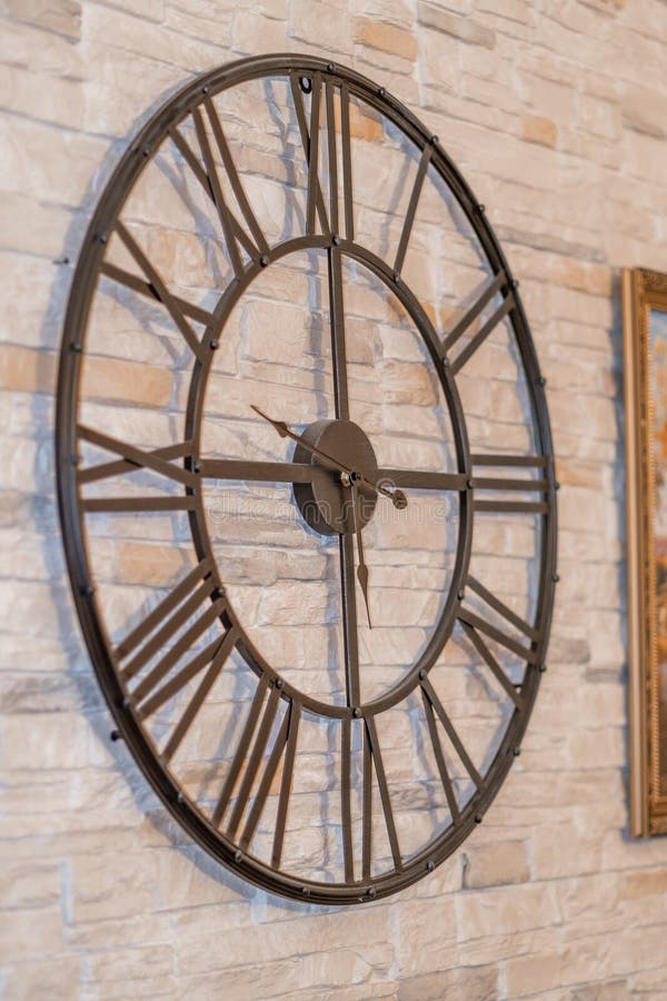 Large Wall Clock with Roman Numerals Against a Textured Stone ...