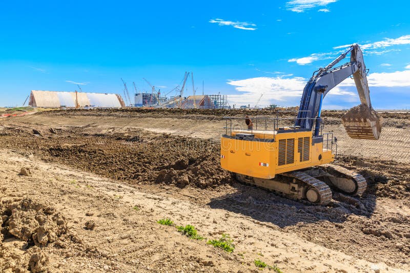 A Large Construction Machine is Digging into the Ground, with the Sky ...