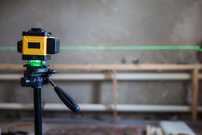 A Laser Level Mounted on a Tripod Projects a Green Line Onto a ...