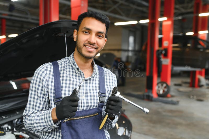 Latin Hispanic Auto Mechanic in Uniform is Examining a Car while ...