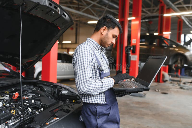 Latin Hispanic Auto Mechanic in Uniform is Examining a Car while ...