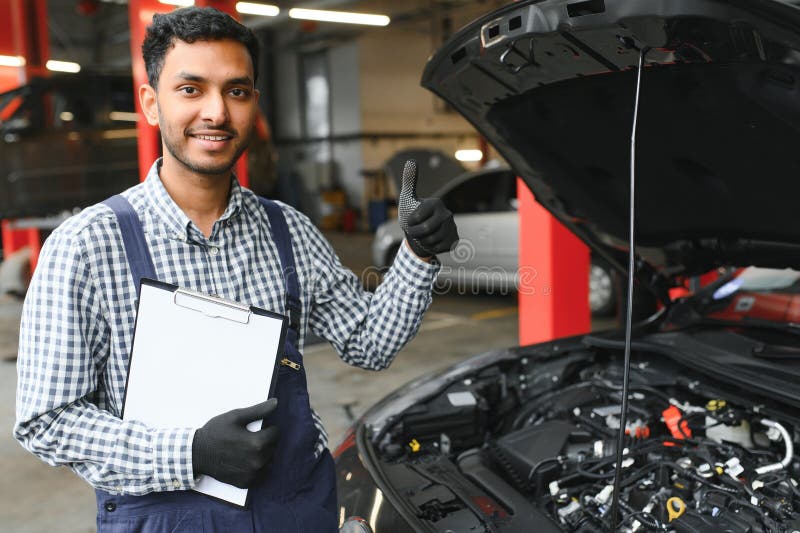 Latin Hispanic Auto Mechanic in Uniform is Examining a Car while ...