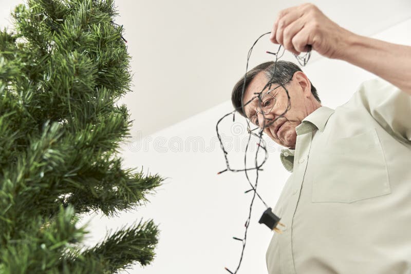 Latin Senior Man Stretching a String of Lights To Put on His Christmas ...