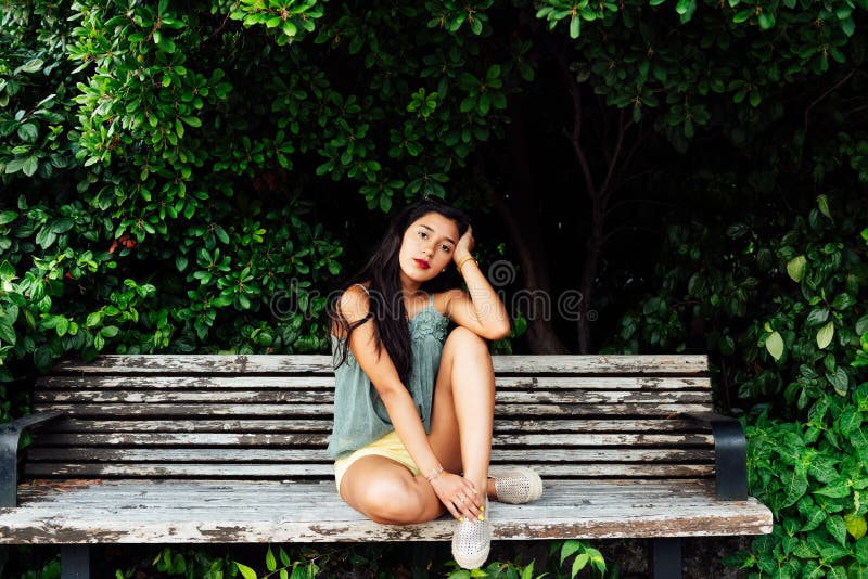 Latin Young Girl With Long Black Hair And Blue Dress Sitting On Wooden
