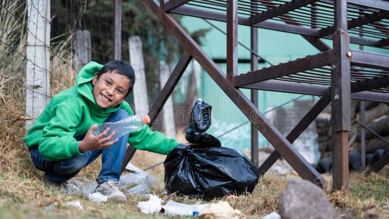 Latino Boy Kneeling while Picking Up a Plastic Bottle Cleaning the Park ...
