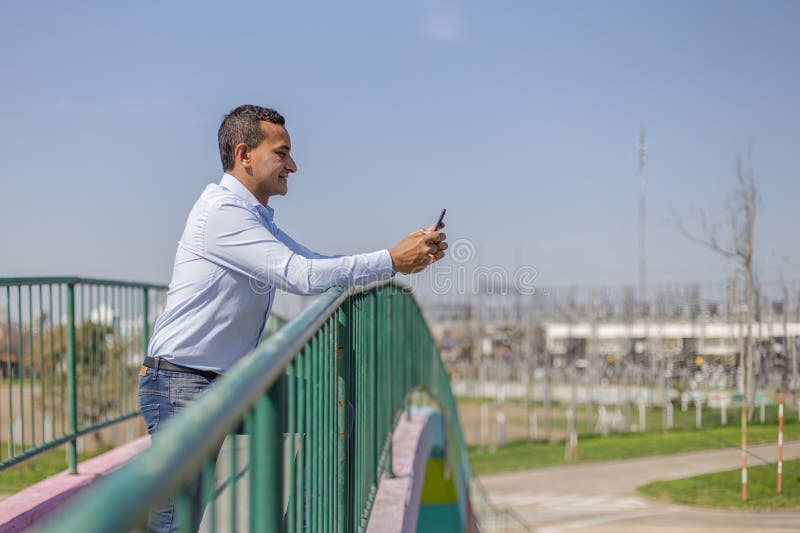 Latino Man in a Shirt Leaning on the Railing of a Pedestrian Bridge ...
