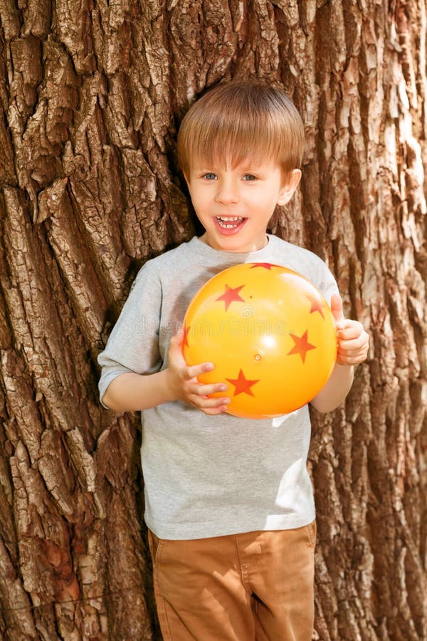 Boy Under Tree with Rubber Ball Pointing Upwards Stock Photo - Image of ...