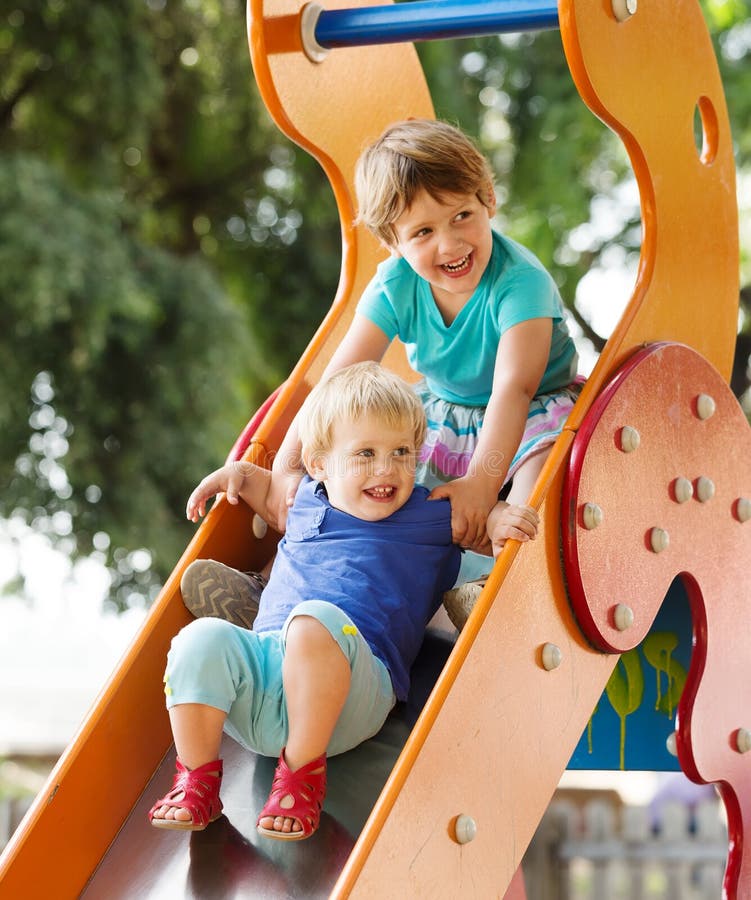 Laughing children on slide stock image. Image of sibling - 73925991