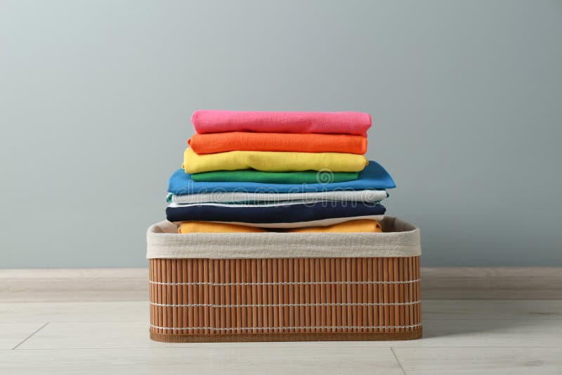 Laundry Basket with Clean Stacked Clothes on Floor Near Grey Wall Stock ...