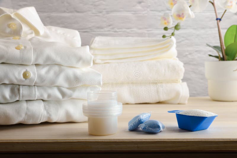Laundry Detergents on Wooden Table with Freshly Washed Folded Clothes ...