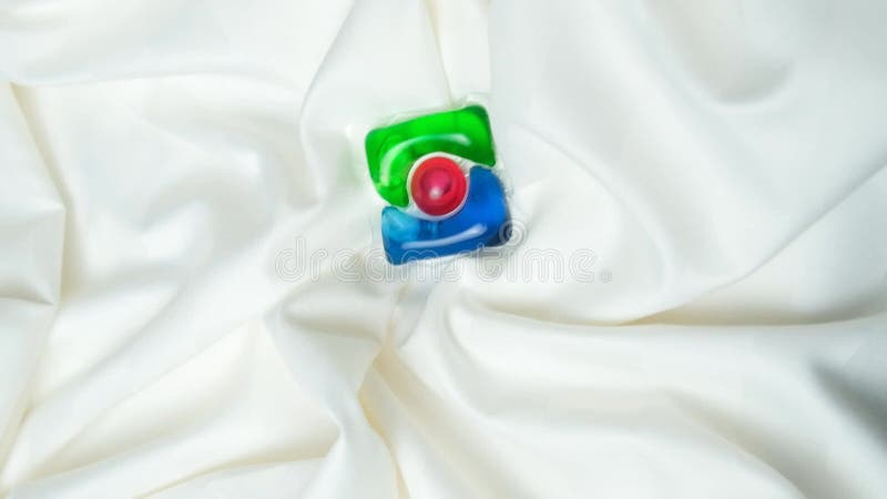 Laundry Pod Slowly Falling on Satin Fabric, Vertical Slow Motion Stock ...