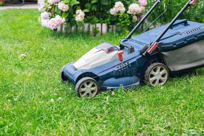 Lawn Mower Cutting Green Grass in Backyard. Gardening Background. Stock ...