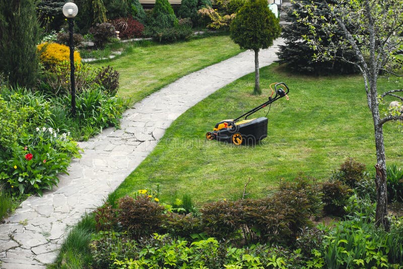 Lawn Mower in the Garden with Trees and Flowers Stock Photo - Image of ...