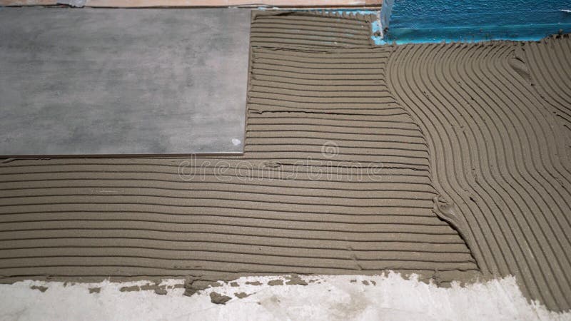 Laying Ceramic Tile on a Notched Adhesive Surface for Home Renovation ...