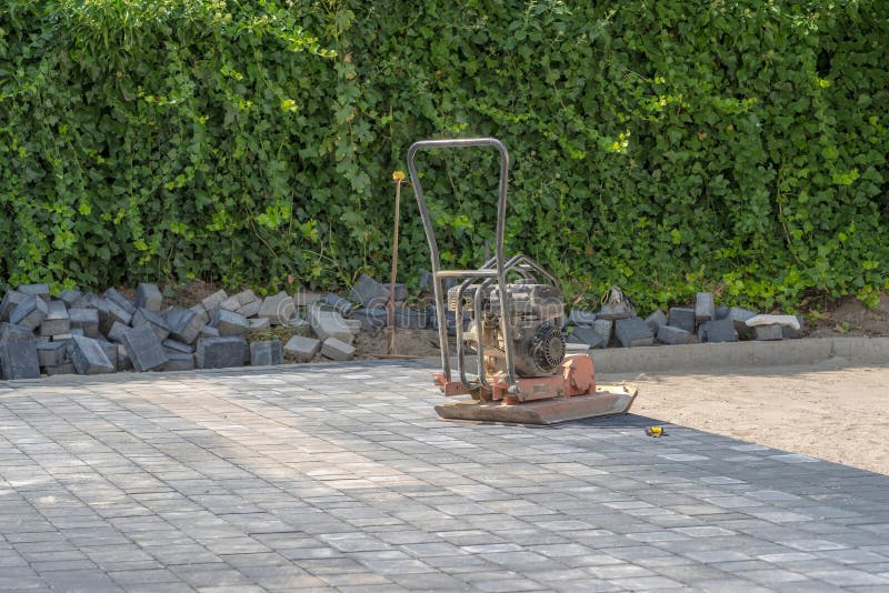 Laying Paving Stones on a Plot Fenced with a Net Covered with Ivy ...