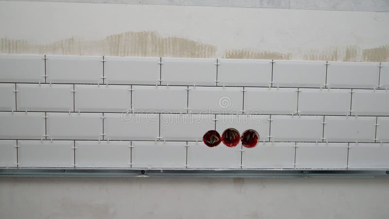Laying White Ceramic Tiles on Wall with Holes for Electrical Outlets ...