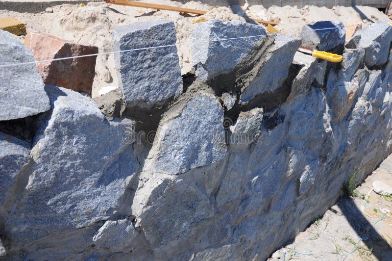 Laying Wild Rock Blocks for House Wall Foundation with Concrete Stock ...