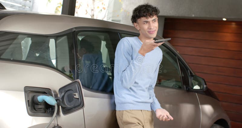Leaning on Electric Car, Man Using Smartphone Voice Assistant in Garage ...