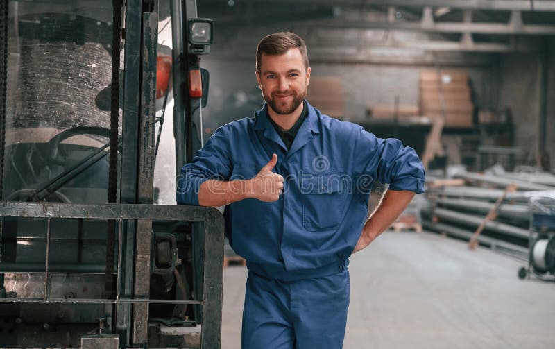 Leaning on the Forklift. Factory Worker in Blue Uniform is Indoors ...