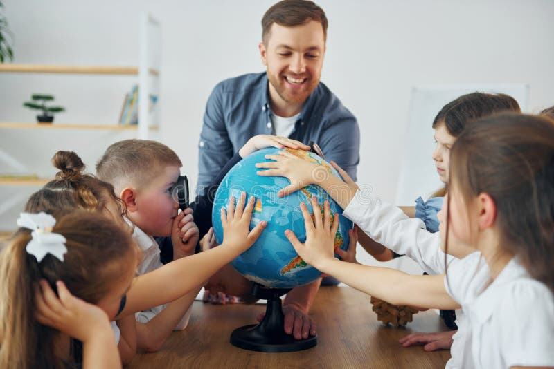 Learning Geography by Using Earth Globe. Group of Children Students in ...