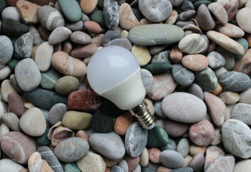 Energy Saving Lamp Bulb on a Colored Smooth Pebbles Texture Background ...