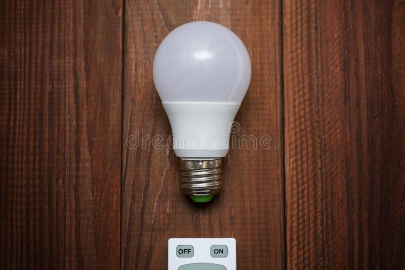 LED Light Bulb and Remote Control with Buttons on and Off on a Wooden ...