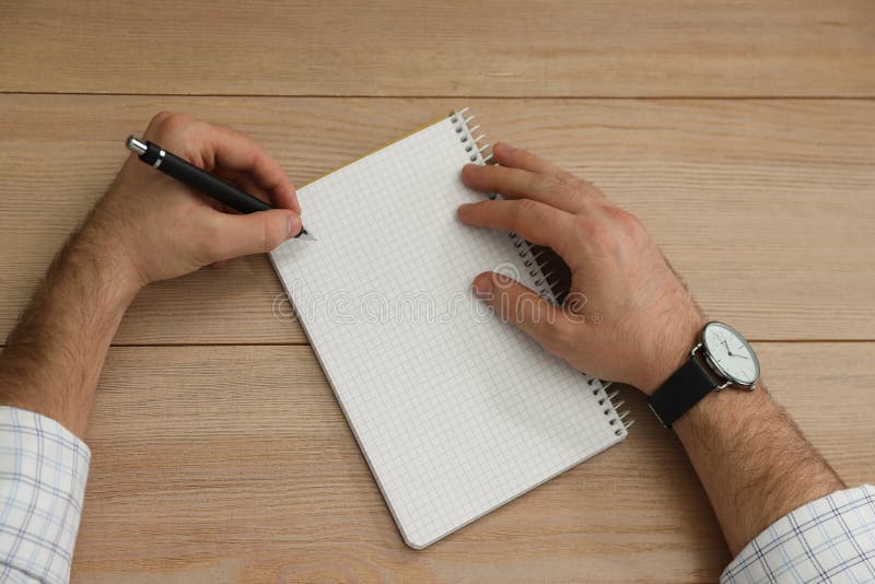Left-handed Man Writing in Notebook at Wooden Desk, Top View Stock ...
