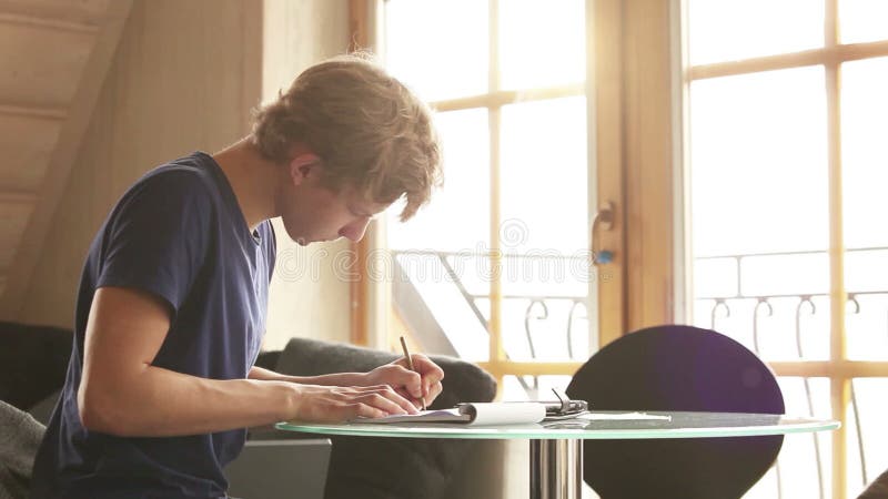 A Left-handed Student Sitting at the Table Doing His Homework, Musing ...