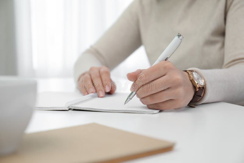 Left-handed Woman Writing in Notebook at Table Indoors, Closeup. Space ...