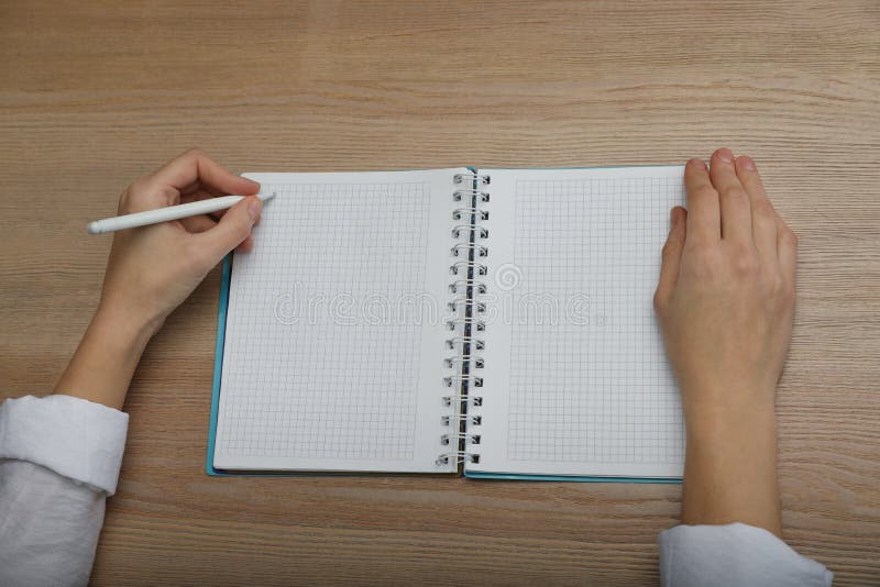 Left-handed Woman Writing in Notebook at Wooden Table, Above View Stock ...