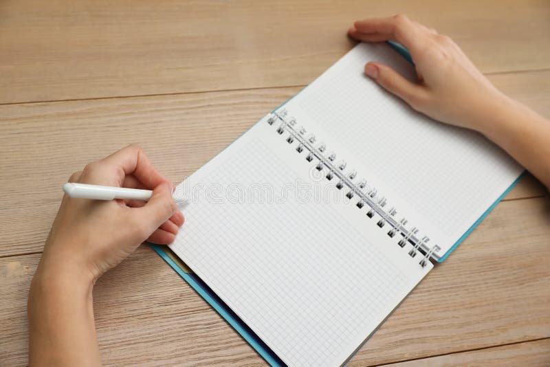 Left-handed Woman Writing in Notebook at Wooden Table, Closeup Stock ...