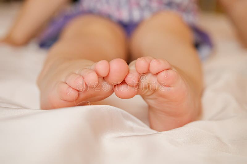 Legs of a Small Child, the Baby is Sitting on a Crib in a Bright Room ...