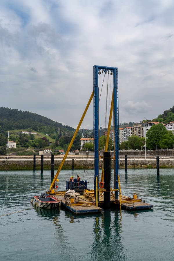 Cosntruction Workers Mount Harbor Pylons with a Floating Pile Driver in ...