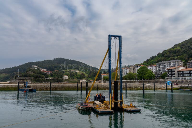 Cosntruction Workers Mount Harbor Pylons with a Floating Pile Driver in ...