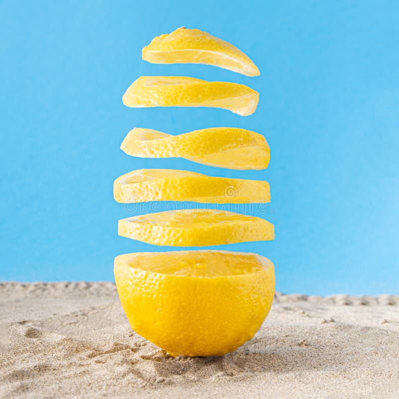 Lemon on Beach Sand with Slices Floating in the Air on a Pastel Blue ...