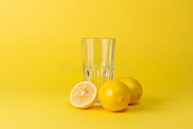 Lemons and Empty Glass Cup on a Yellow Background Stock Photo - Image ...