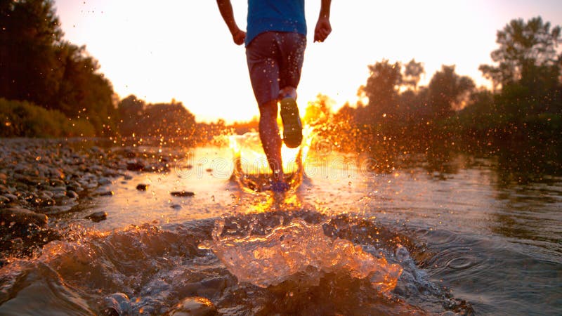 LOW ANGLE, DOF: Unrecognizable Male Runner Splashing the Glassy River ... LOW ANGLE, DOF: Unrecognizable Male Runner Splashing the Glassy River ...