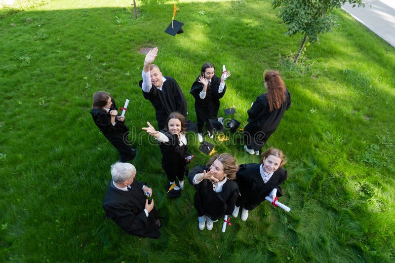 Les Camarades De Classe Dans Les Robes De Graduation Jettent Leur