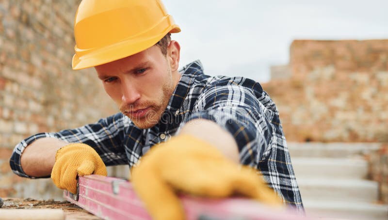 With Level Measuring Tool. Construction Worker in Uniform and Safety ...