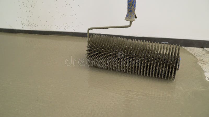 Leveling the Floor Using Spiked Roller. Construction Worker Mixes ...