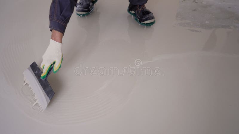 A Worker Spreads Liquid on the Floor with a Spatula. Leveling Liquid ...